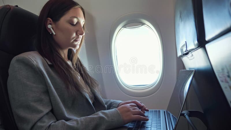 Brunette Woman In A Suit And A Wireless Earphone In Ear Is Typing Text