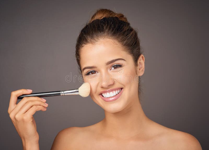 Brushing on Rosy Cheeks. Portrait of a Beautiful Young Model Applying ...