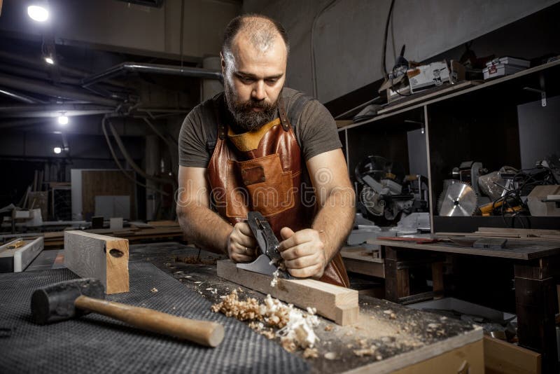 Brutal Master Carpenter in an Apron Planes Tree with a Plane in ...