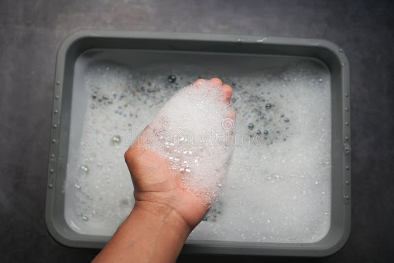 Bubbles Form in Hand Above a Gray Basin Filled with Soapy Water Stock ...