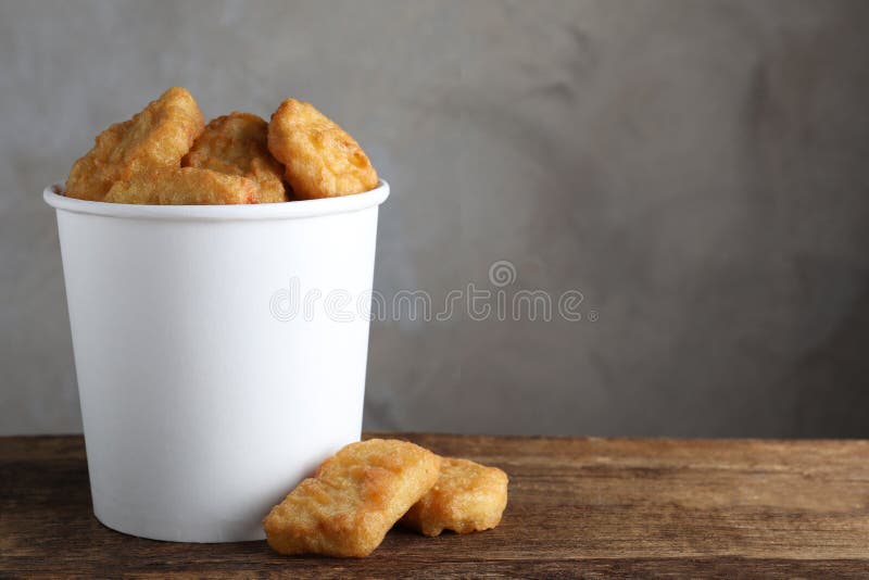 Bucket with Delicious Chicken Nuggets on Table. Space for Text Stock ...