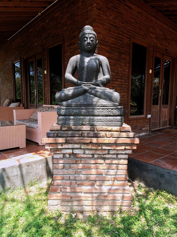 A Buddha Statue Sitting Cross-legged in the Courtyard of a Cottage ...