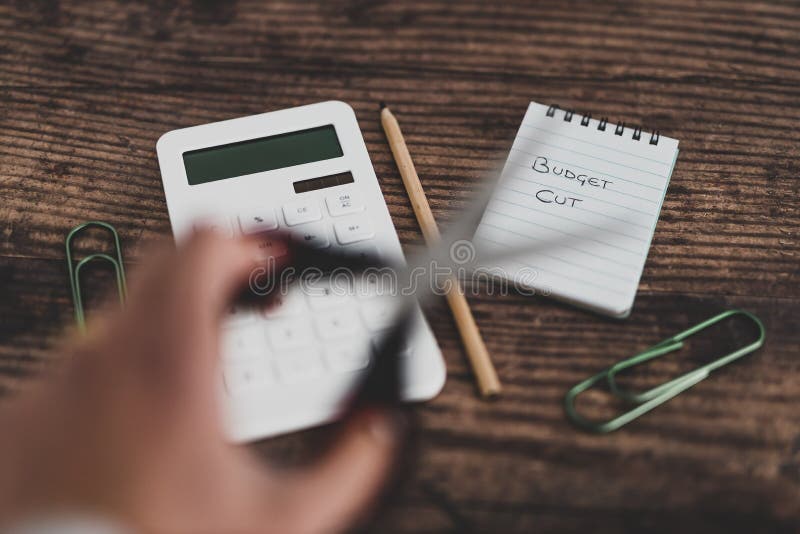 Budget Cuts Text on Notepad Next To Calculator and Unfocused Scissors ...