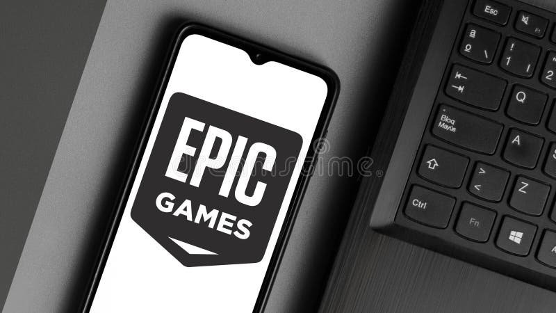 Epic Games Logo is Displayed on a Smartphone Screen with a Notebook on ...