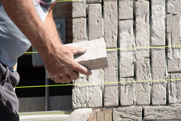 Builder Aligning Bricks on Wall with Level, Tools in Background ...