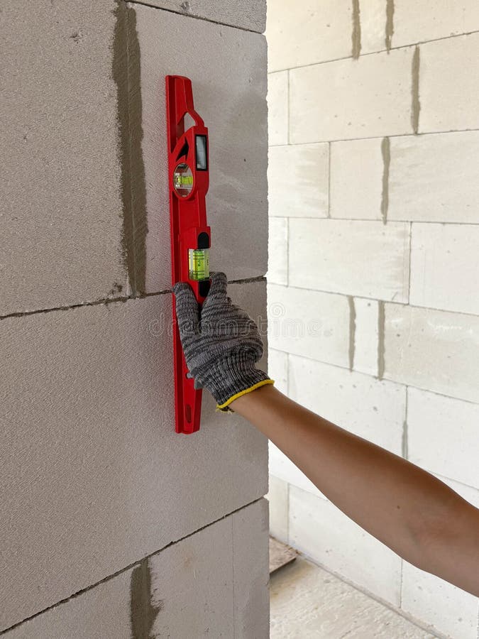 A Builder Applies a Bubble Level To a New Wall at a Construction Site ...