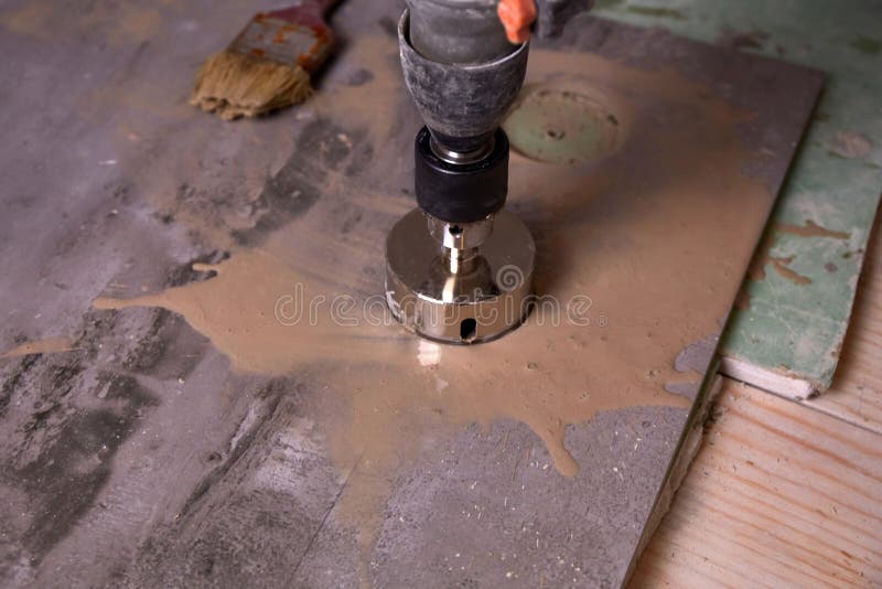 A Builder Cuts a Round Hole in a Porcelain Tile Using a Power Tool ...