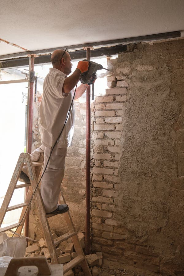 Builder with Demolition Hammer Breaking a House Wall. Stock Image ...