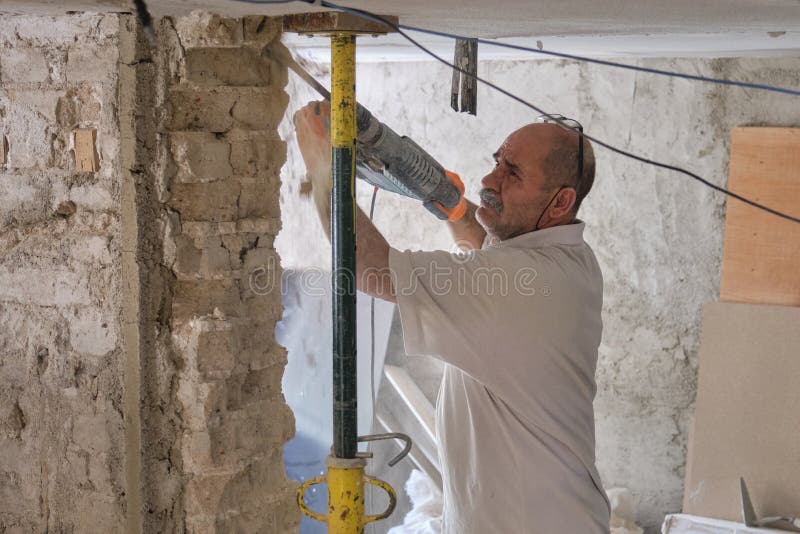 Builder with Demolition Hammer Breaking a House Wall. Stock Photo ...