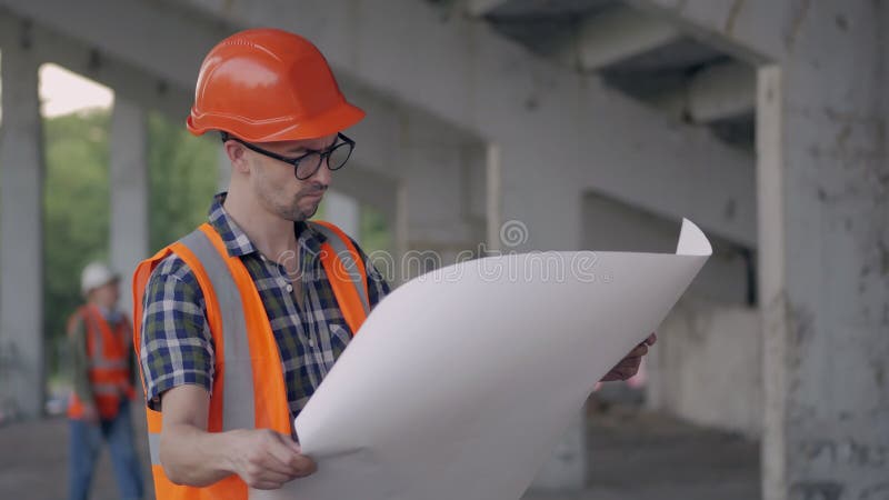 Builder Engineer in a Hard Hat with a Drawing on the Construction Site ...
