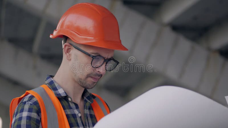 Builder Engineer in a Hard Hat with a Drawing on the Construction Site ...