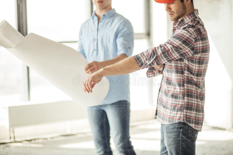 Builder is Going To Work while His Colleague Standing with Blueprint ...
