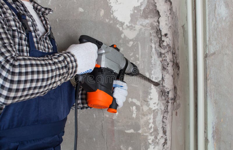 The Builder is Making Hole in Wall at Construction Site with Hammer ...