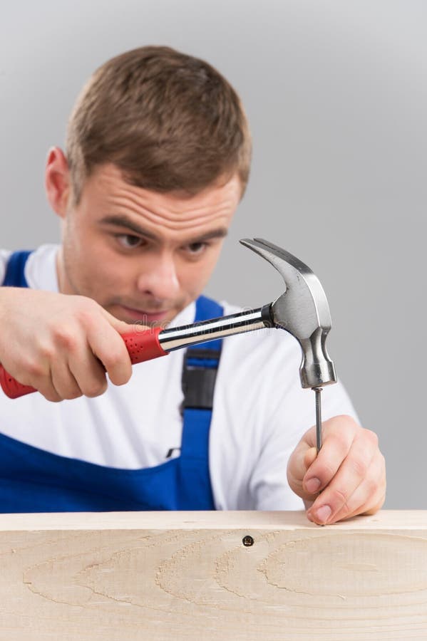 Builder Hammering Nails into Board Isolated on Grey. Stock Photo ...