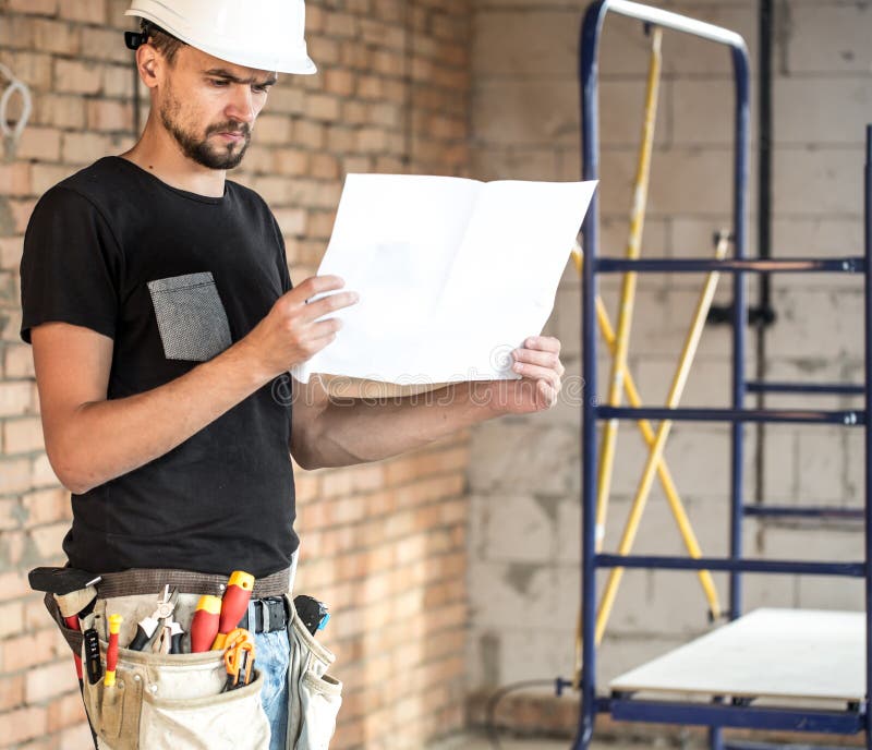 Builder Handyman with Construction Tools, Looking at the Drawings on ...