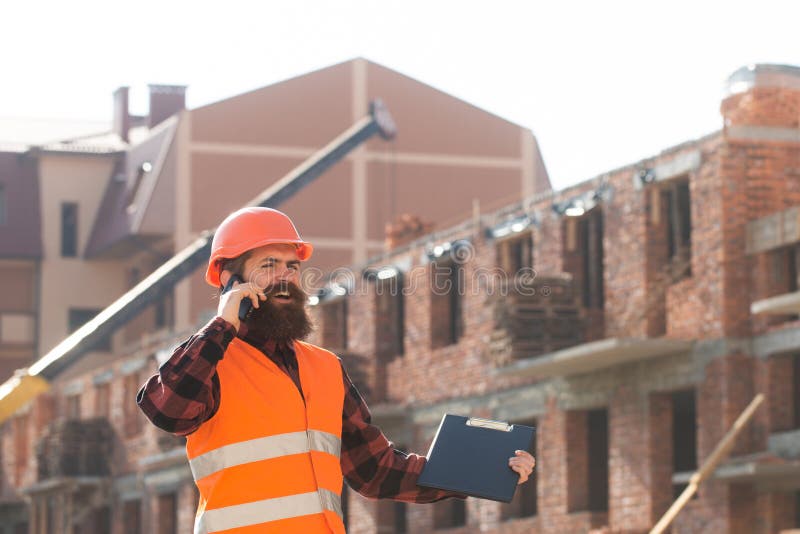 Builder in Hardhat Working at Construction Site, Talking on Phone ...