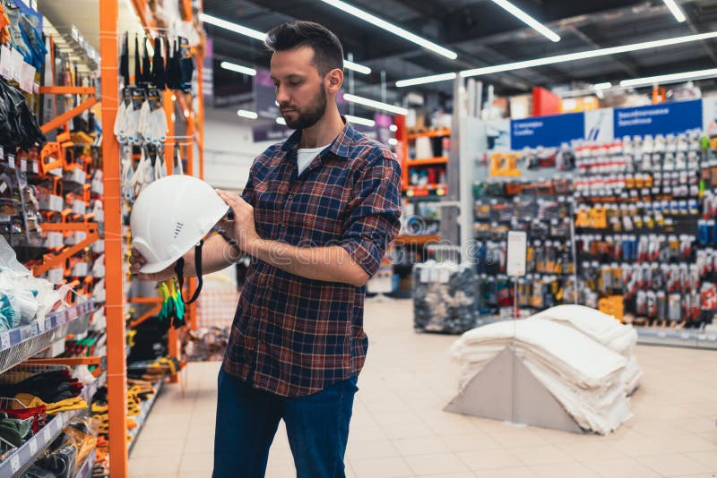 Builder in a Hardware Store Picks Up a Construction Helmet Stock Photo ...