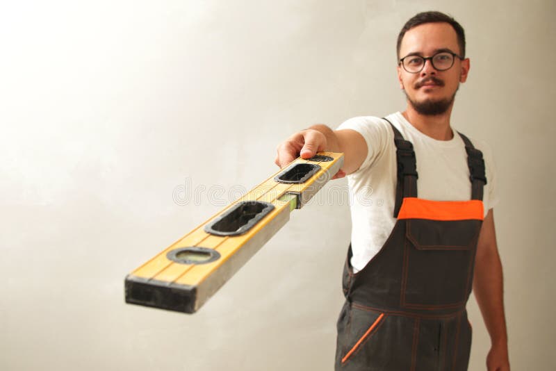 Builder Holding a Level Against a White Wall, Construction Worker ...