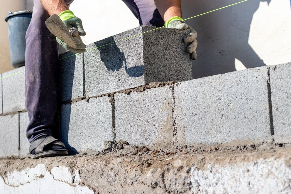 A Builder Holds a Trowel during the Construction of a Wall Made of ...