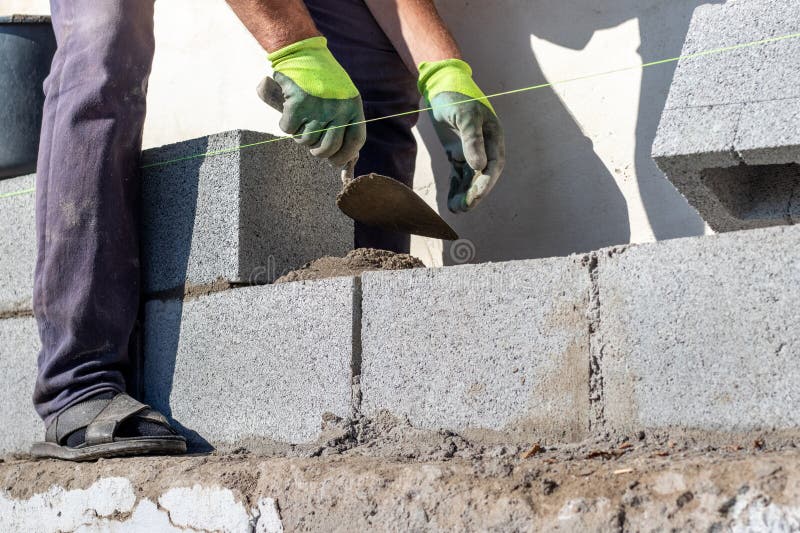 A Builder Holds a Trowel during the Construction of a Wall Made of ...