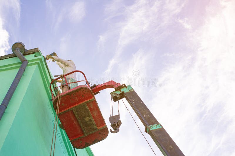 A Builder on a Hydraulic Lift is Repairing a Building, Using a ...