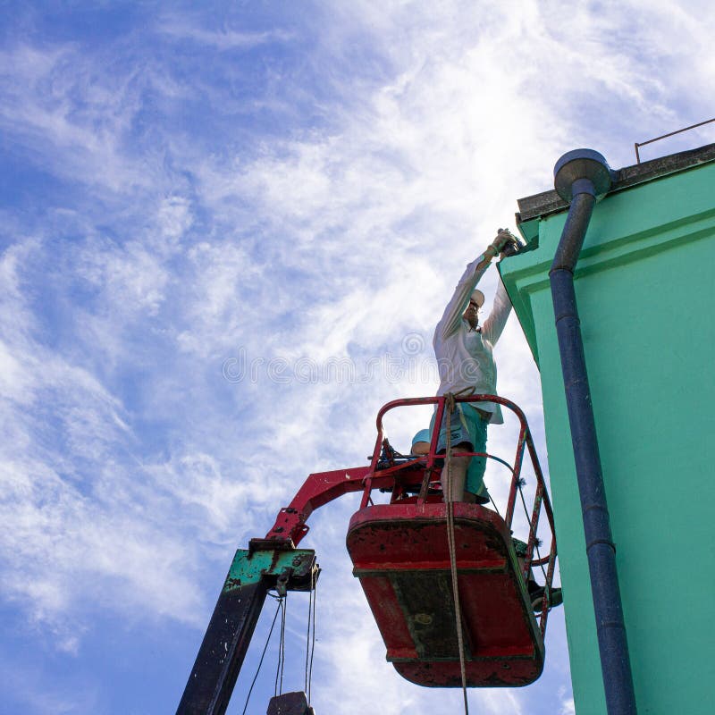 A Builder on a Hydraulic Lift is Repairing a Building, Using a ...