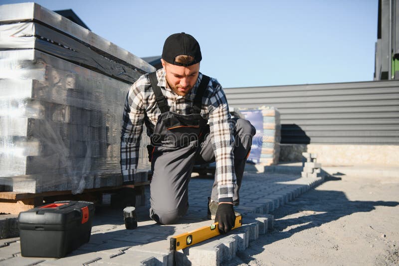 Builder Laying a Paving Brick Placing it on the Sand Foundation with ...