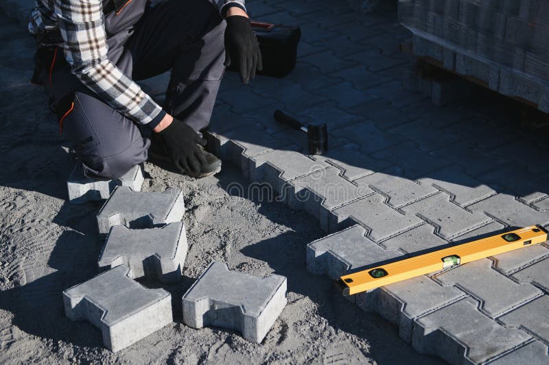 Builder Laying a Paving Brick Placing it on the Sand Foundation with ...
