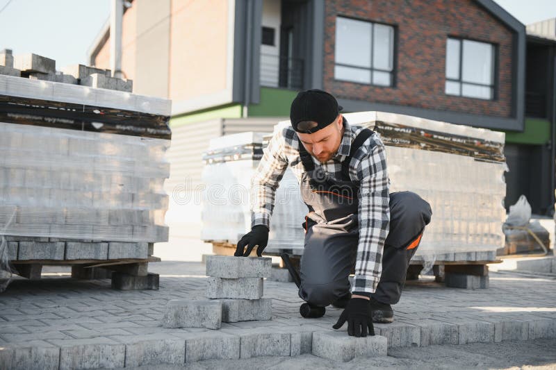 Builder Laying a Paving Brick Placing it on the Sand Foundation with ...