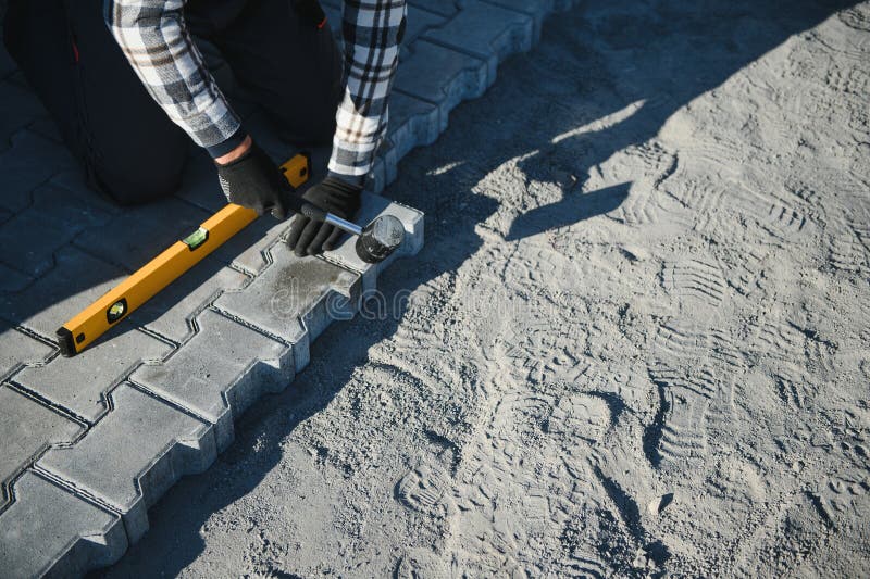 Builder Laying a Paving Brick Placing it on the Sand Foundation with ...