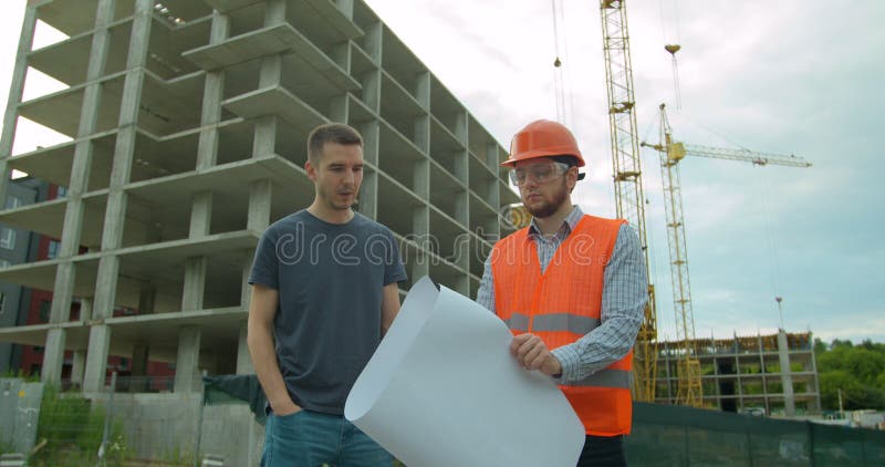 Builder with a Male Client Near Building Under Construction Outdoors ...