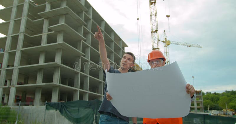Builder with a Male Client Near Building Under Construction Outdoors ...