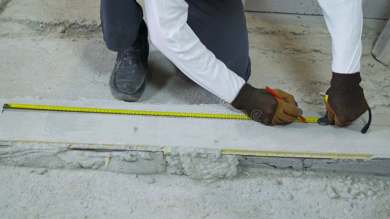 Builder Measures Distances with Measuring Tape and Pencil at ...