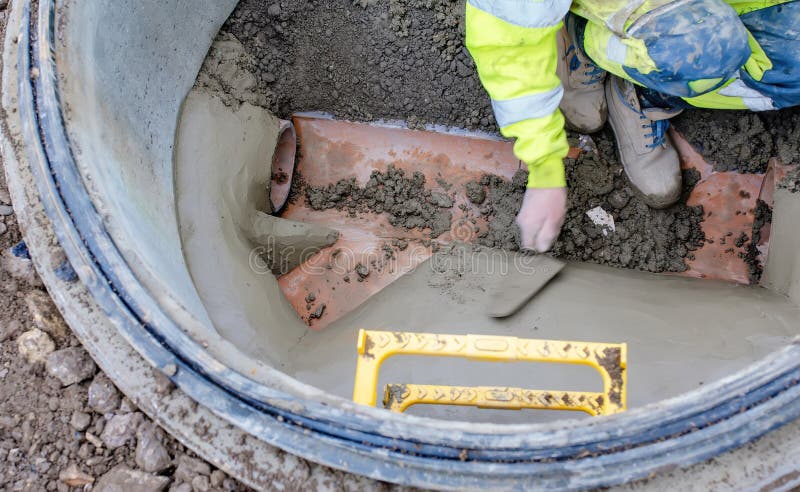 A Builder in the New Built Manhole Benching it with Sand and Cement Mix ...