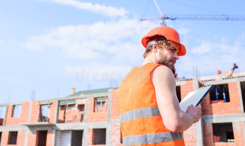 Builder Orange Vest and Helmet Works at Construction Site. Control ...