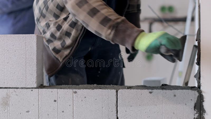 The Builder Places the Block during the Construction of the Wall. Stock ...