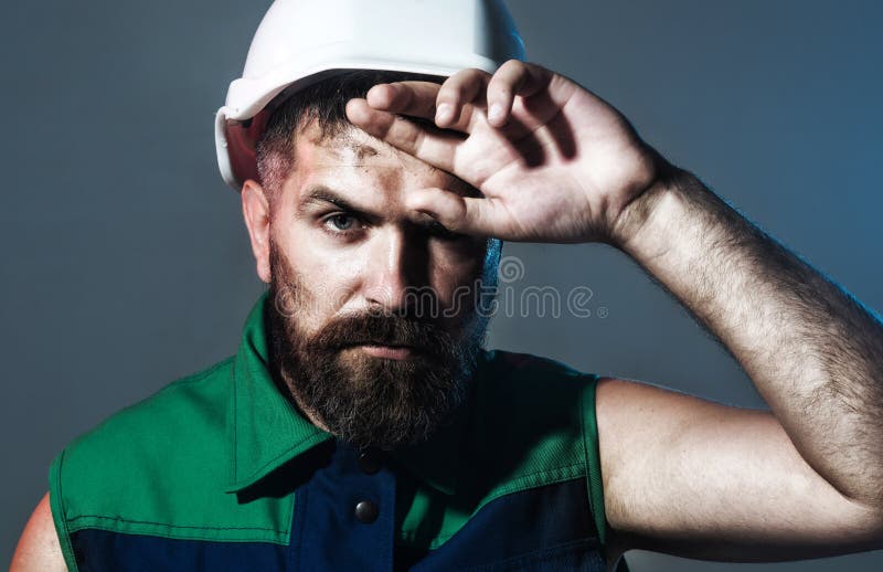 Builder in Protective Clothing and Hardhat. Male Builder Wipes Sweat ...