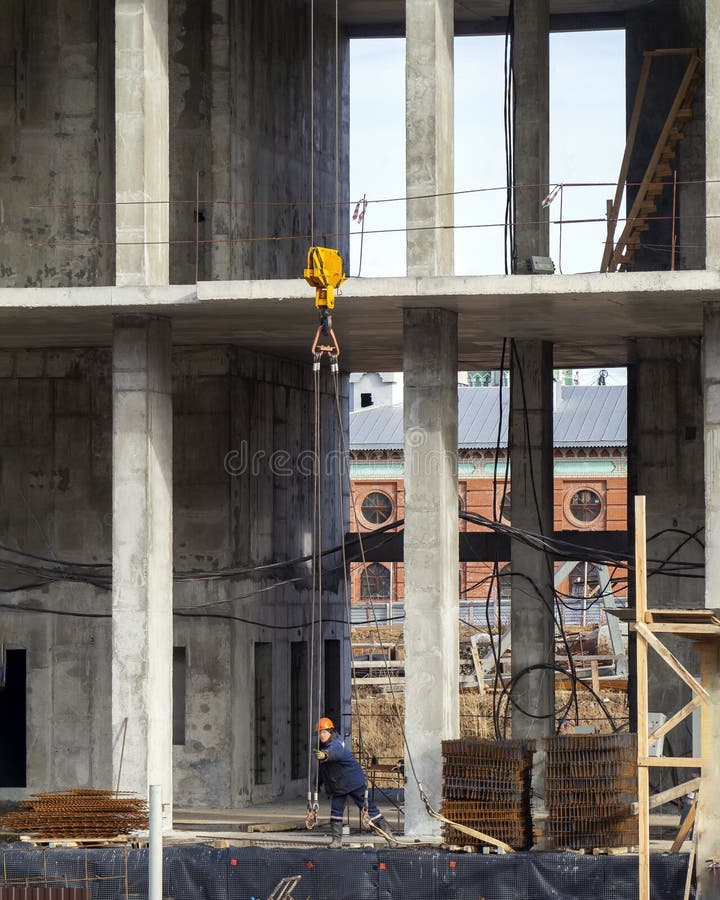 The Builder Pulls a Metal Cable with Hooks Towards Him To Pick Up and ...
