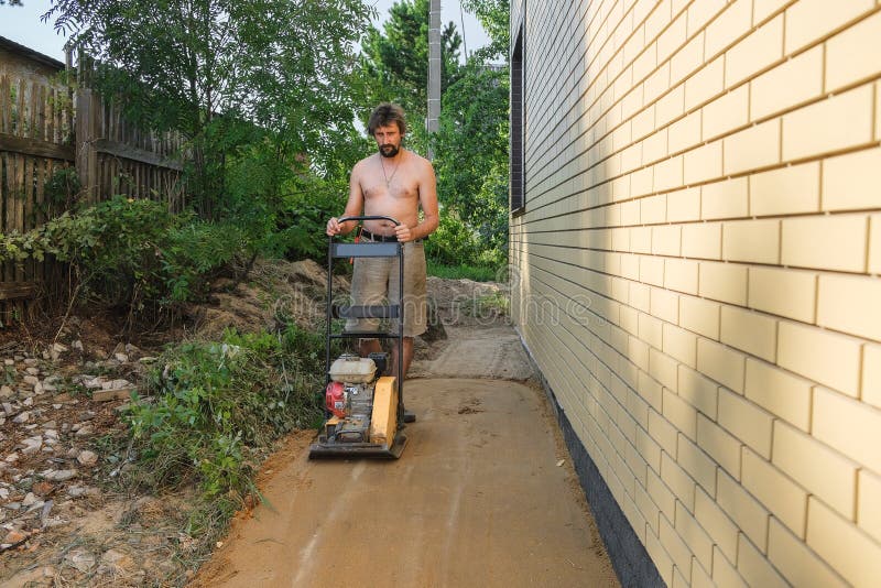 Builder Ramming Sand Around the House at the Construction Site Stock ...