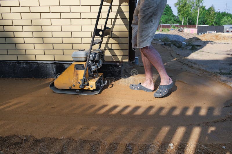 Builder Ramming Sand Around the House at the Construction Site Stock ...