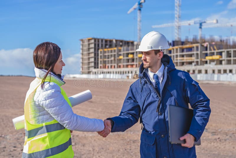 A Builder and a Real Estate Agent Shake Hands in Front of a Building ...