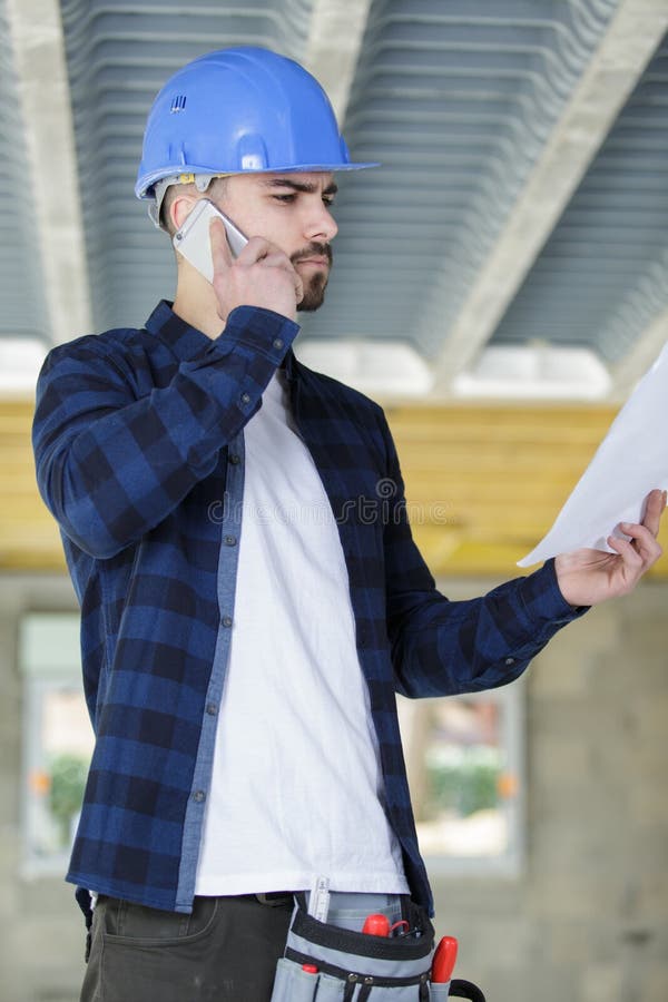 Builder with Smartphone Looking at Plans Stock Image - Image of ...