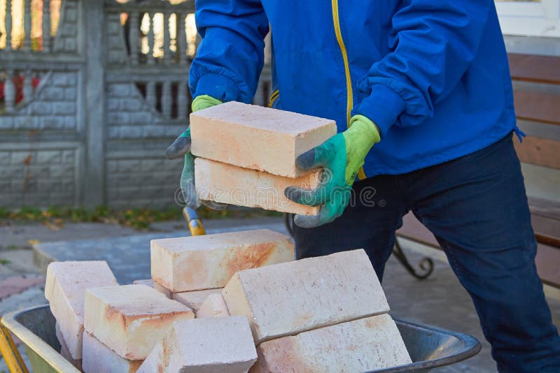 Builder Takes a Brick from a Wheelbarrow,man Helper Unloads Bricks on ...
