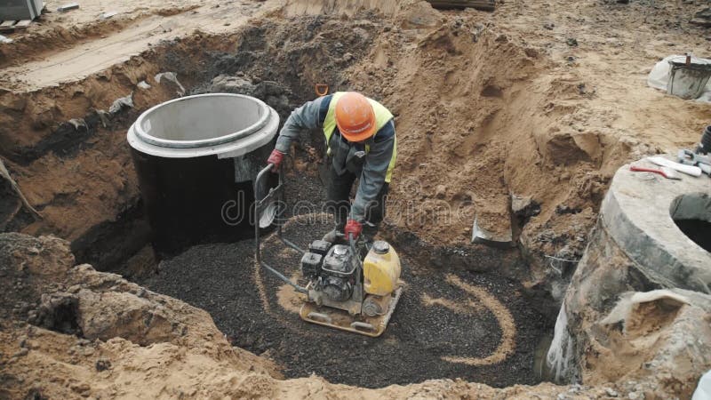 Builder Use Plate Compactor on Macadam in Trench with Concrete Manhole ...