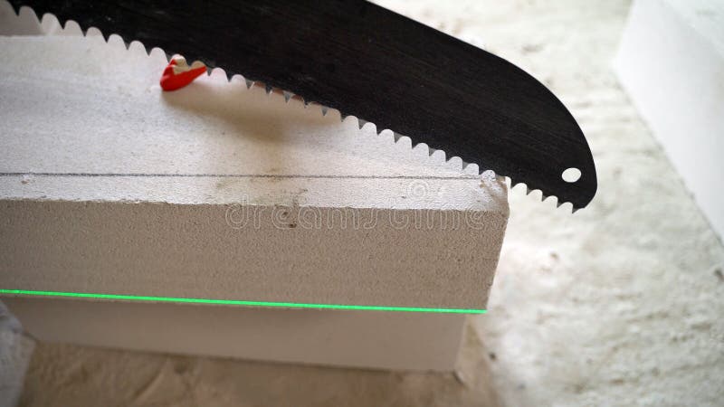 A Construction Worker Saws an Aerated Concrete Block with a Hand Saw at ...