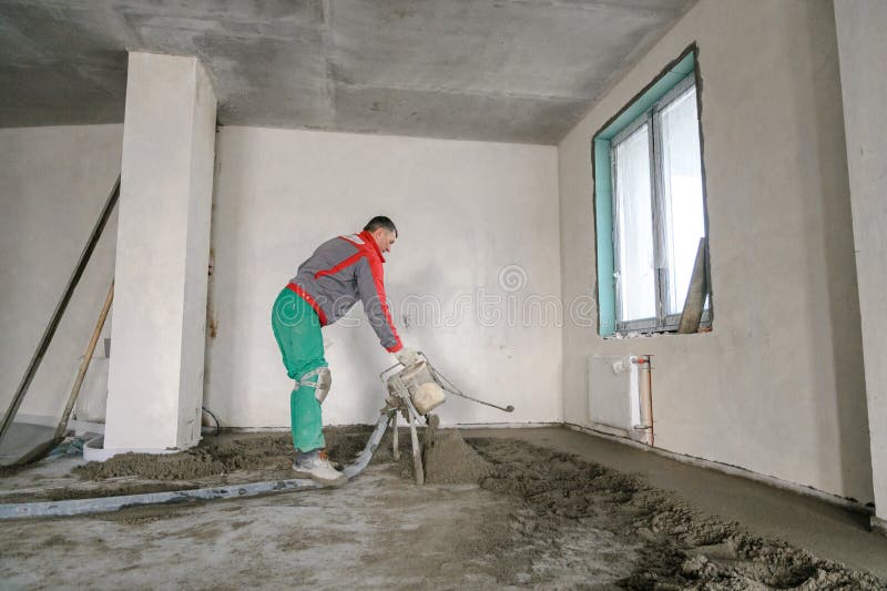 A Builder in Work Clothes is Doing His Job, Leveling the Floor, Pouring ...