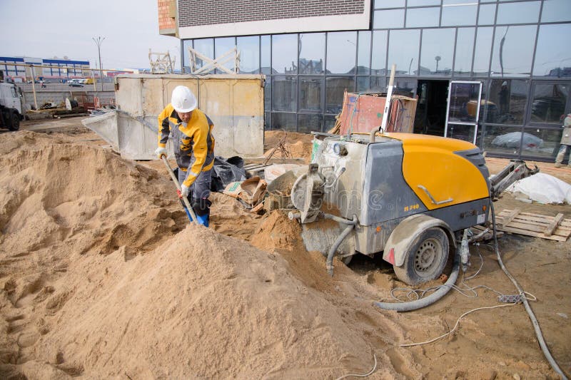 A Builder in Work Clothes is Doing His Job, Leveling the Floor, Pouring ...
