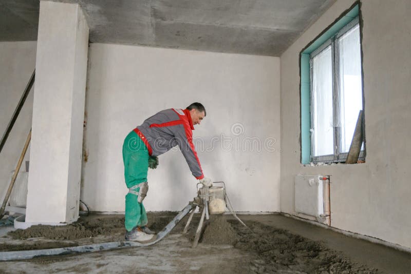 A Builder in Work Clothes is Doing His Job, Leveling the Floor, Pouring ...