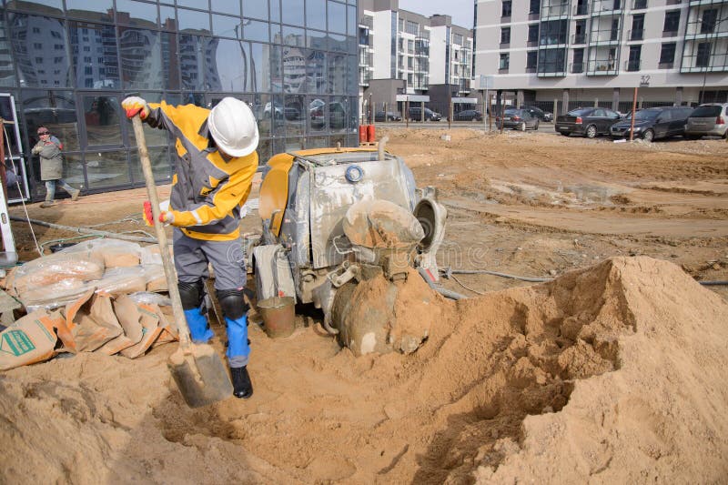 A Builder in Work Clothes is Doing His Job, Leveling the Floor, Pouring ...