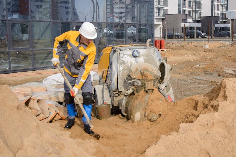 A Builder in Work Clothes is Doing His Job, Leveling the Floor, Pouring ...